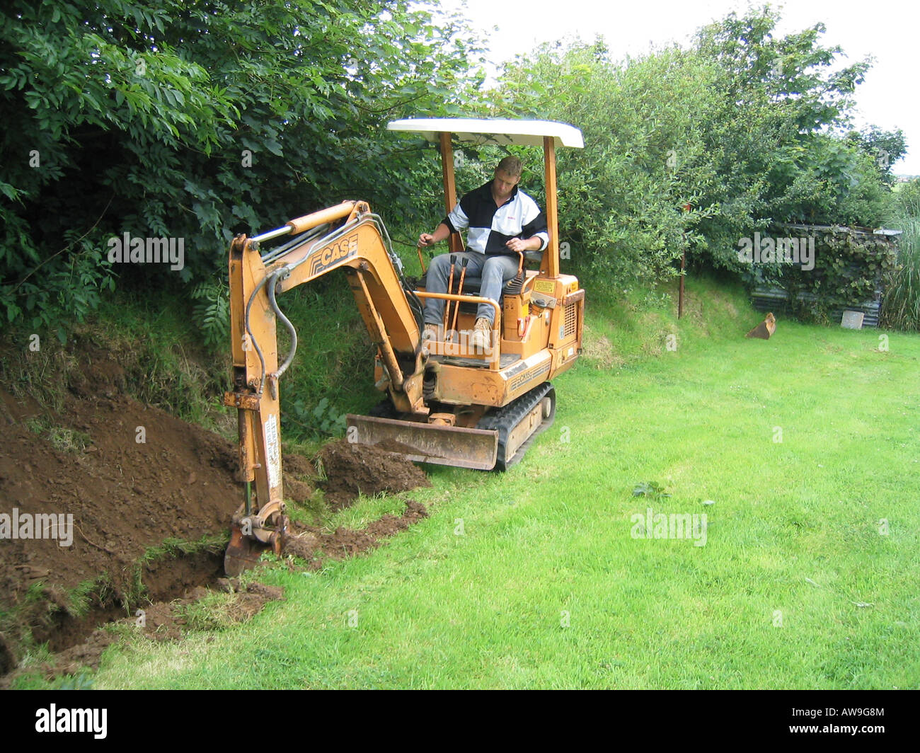 Digger small Caterpilar digging trench in green field for trees Stock ...