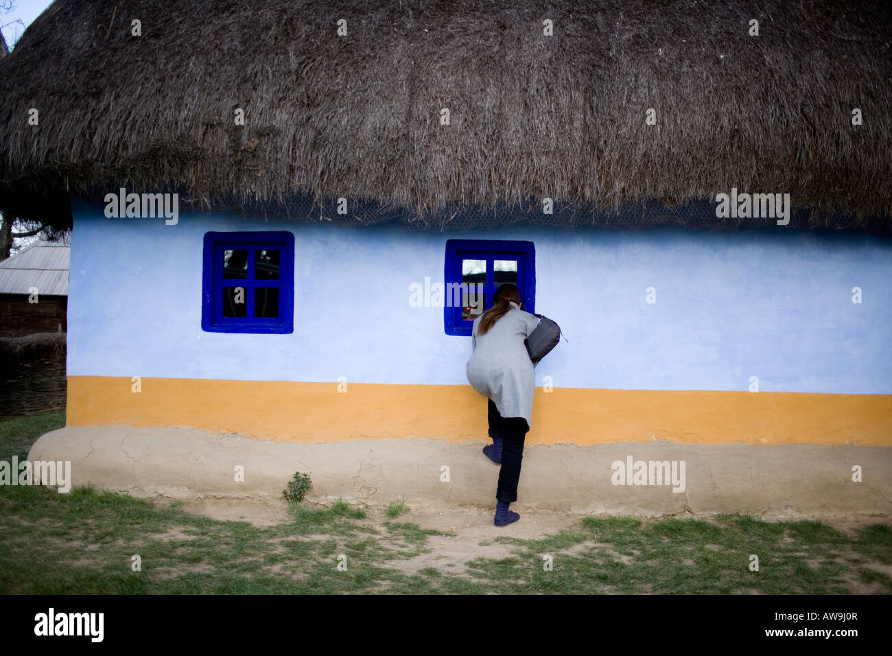 woman in front of a cottage house looking inside the house through a ...