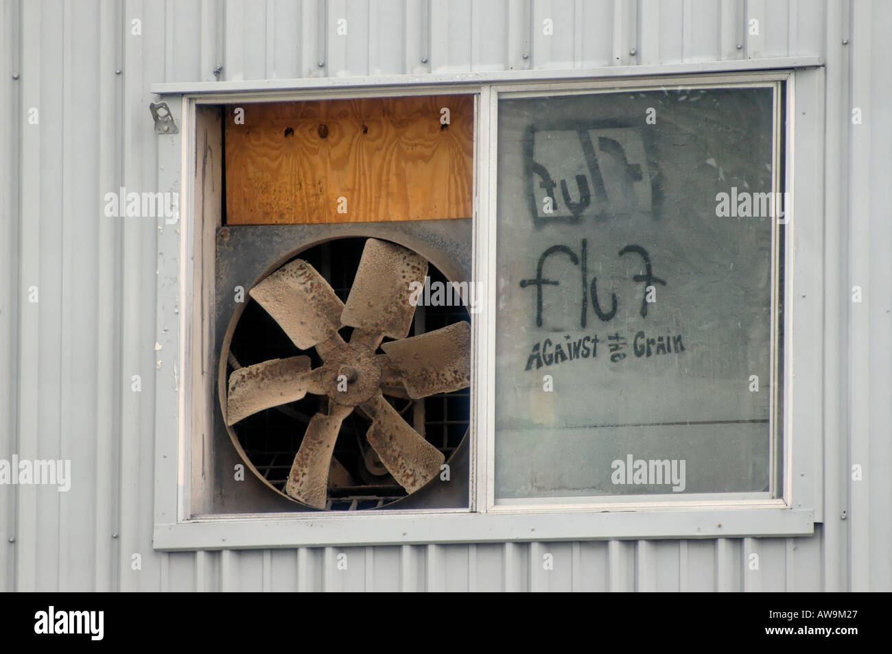 An old, dirty ventilation fan in the window of a commercial building in ...