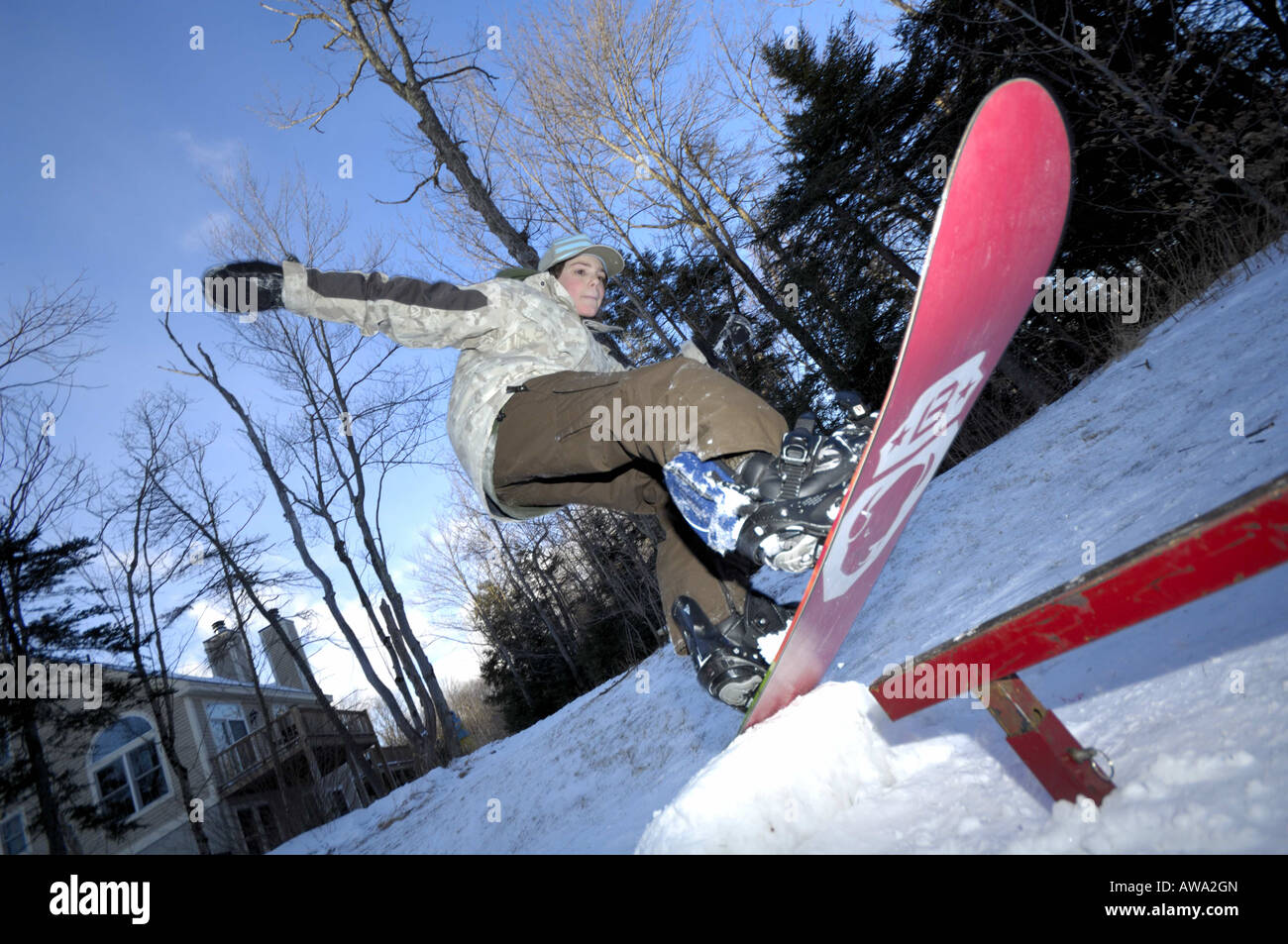 A young male snowboarder performs a freestyle stunt by riding a railing ...
