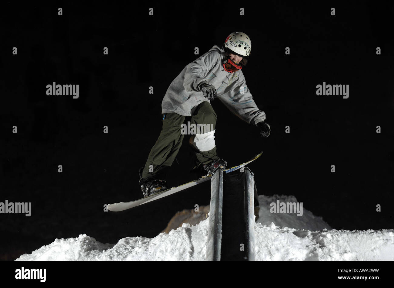 A young male snowboarder performs a freestyle stunt by sliding down or ...