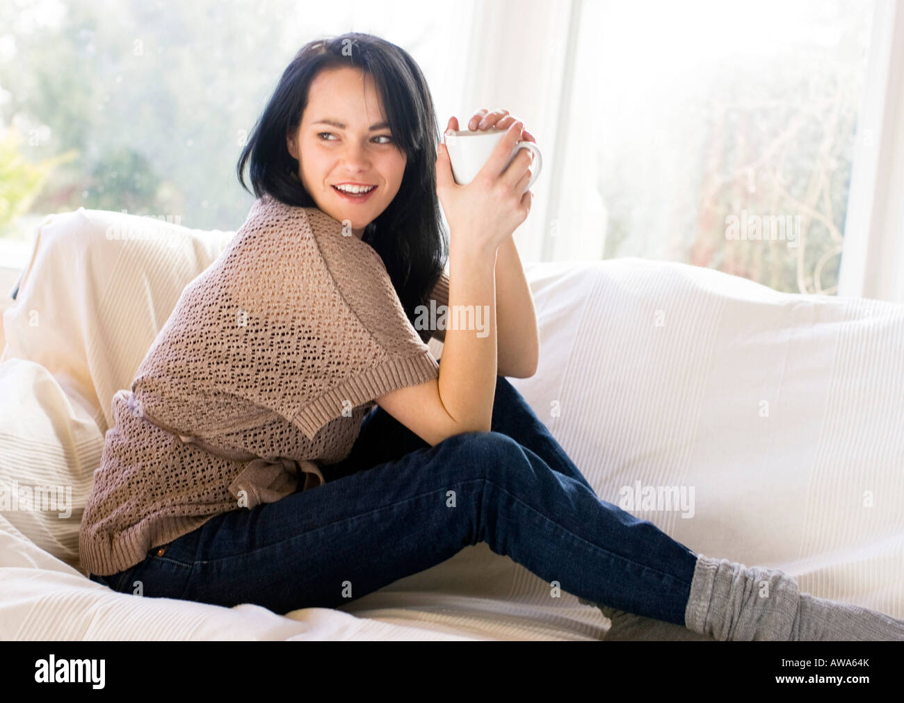 Woman sat on sofa Stock Photo - Alamy