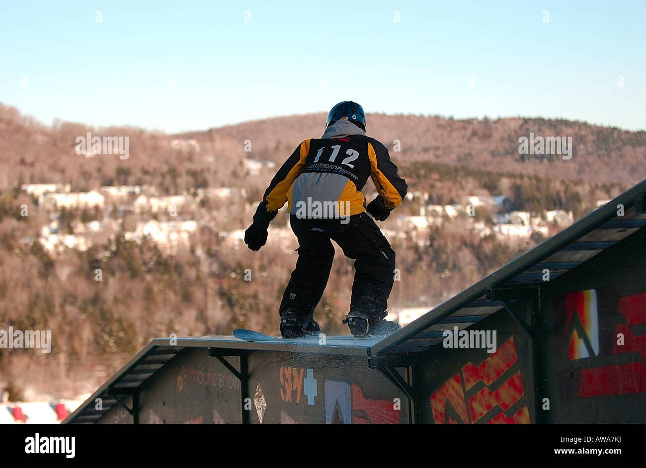 A young male snowboarder performs a freestyle stunt by sliding down or ...