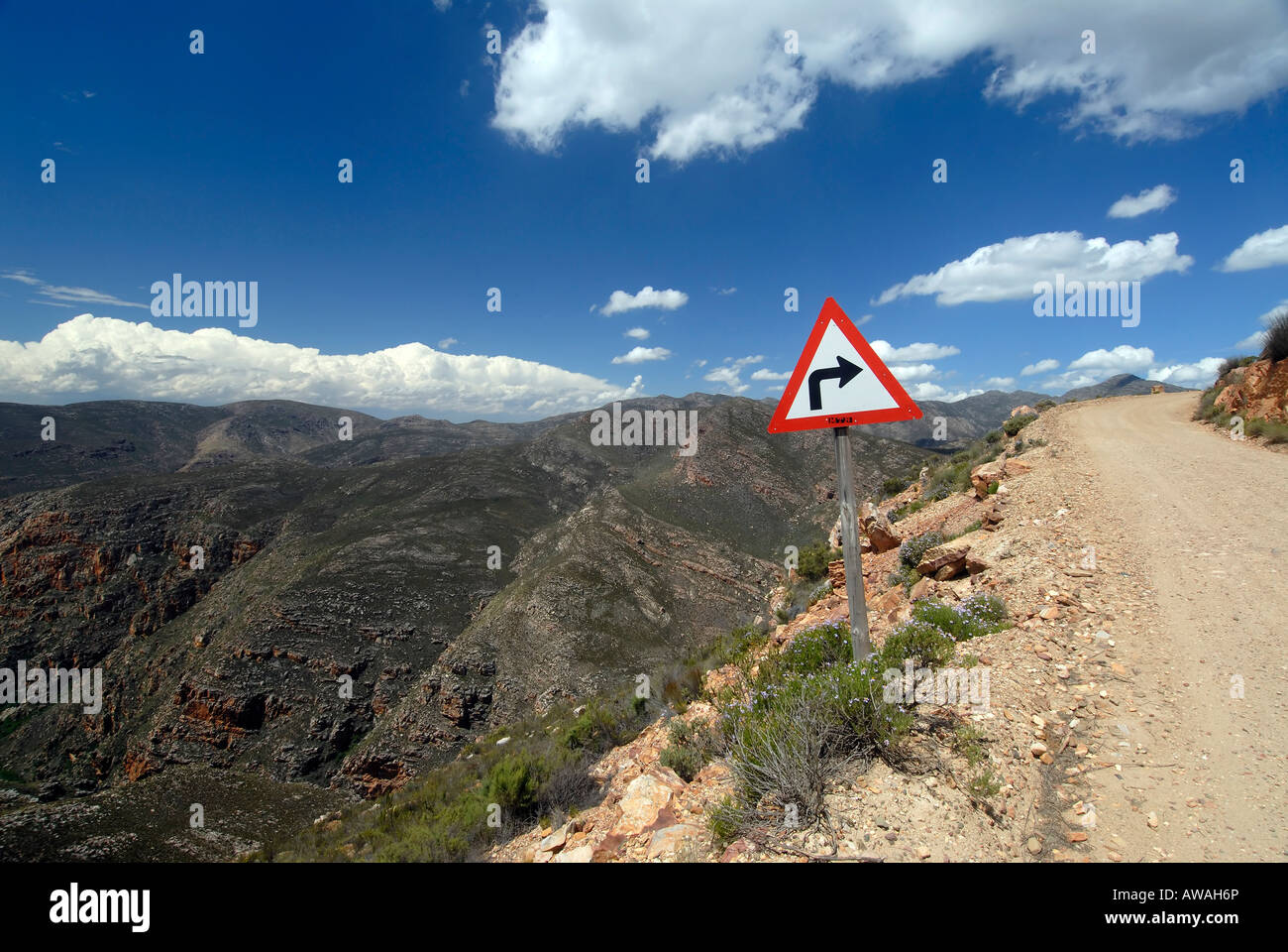 A sign indicating a right angle bend on a stony mountain pass road ...