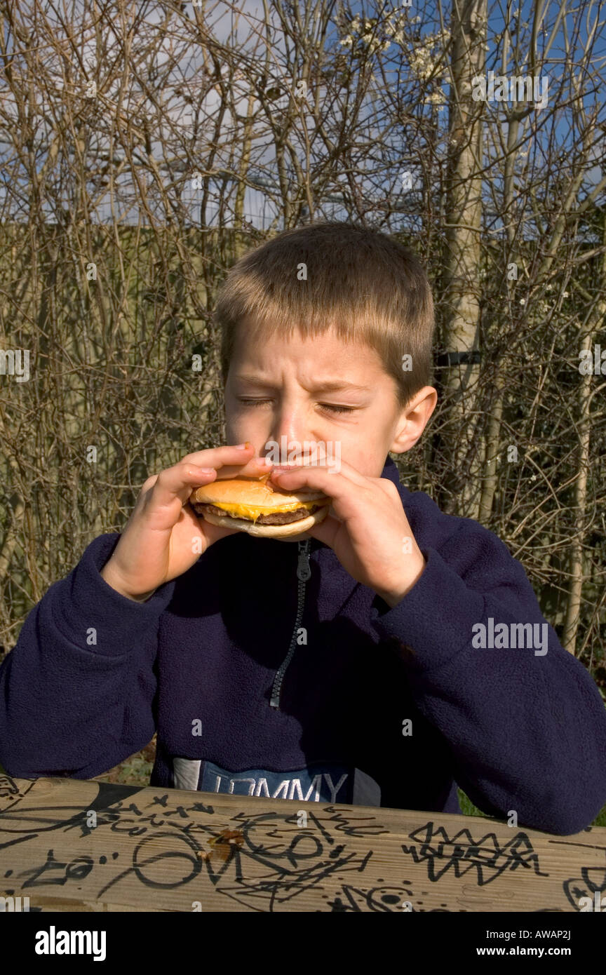a young boy eating a burger outdoors Stock Photo - Alamy