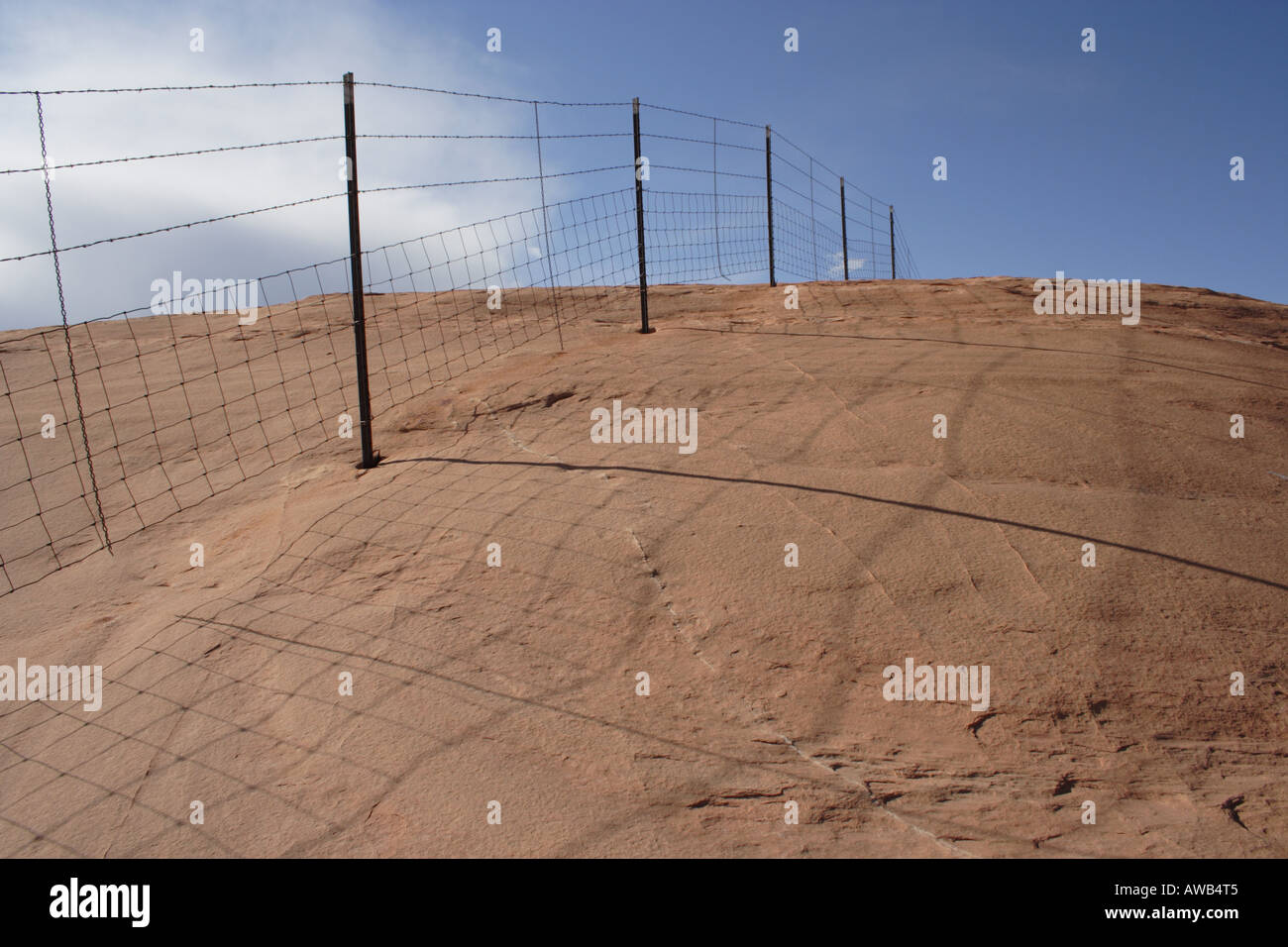 Metal fence punching through a sandstone swell Stock Photo - Alamy