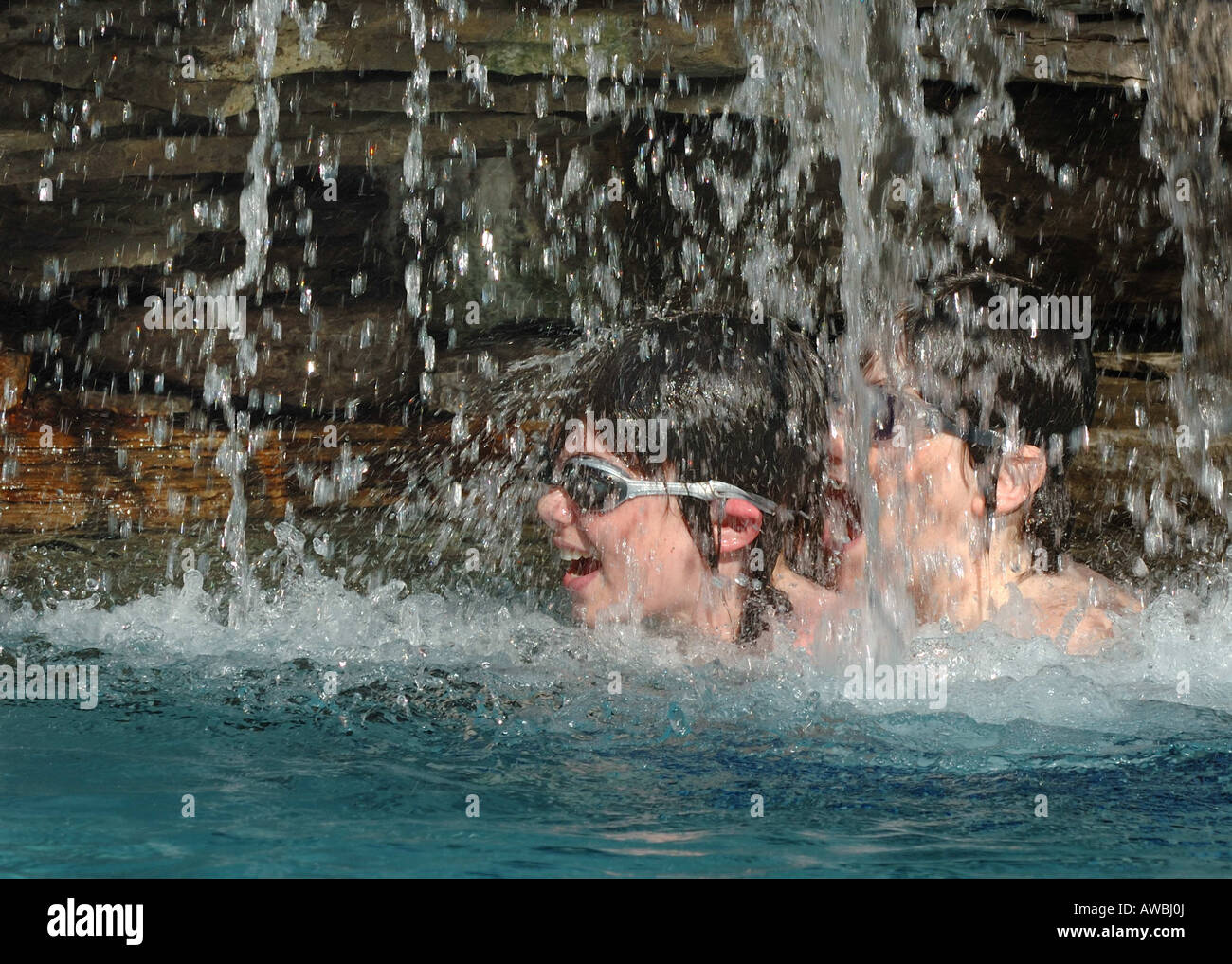 Two boys playing under a waterfall Stock Photo - Alamy