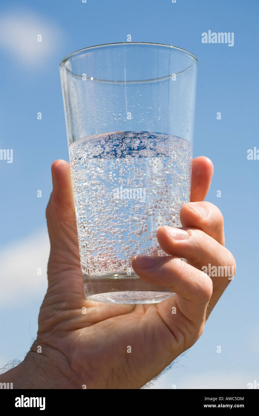 Glass of life giving water held against a blue sky Stock Photo - Alamy