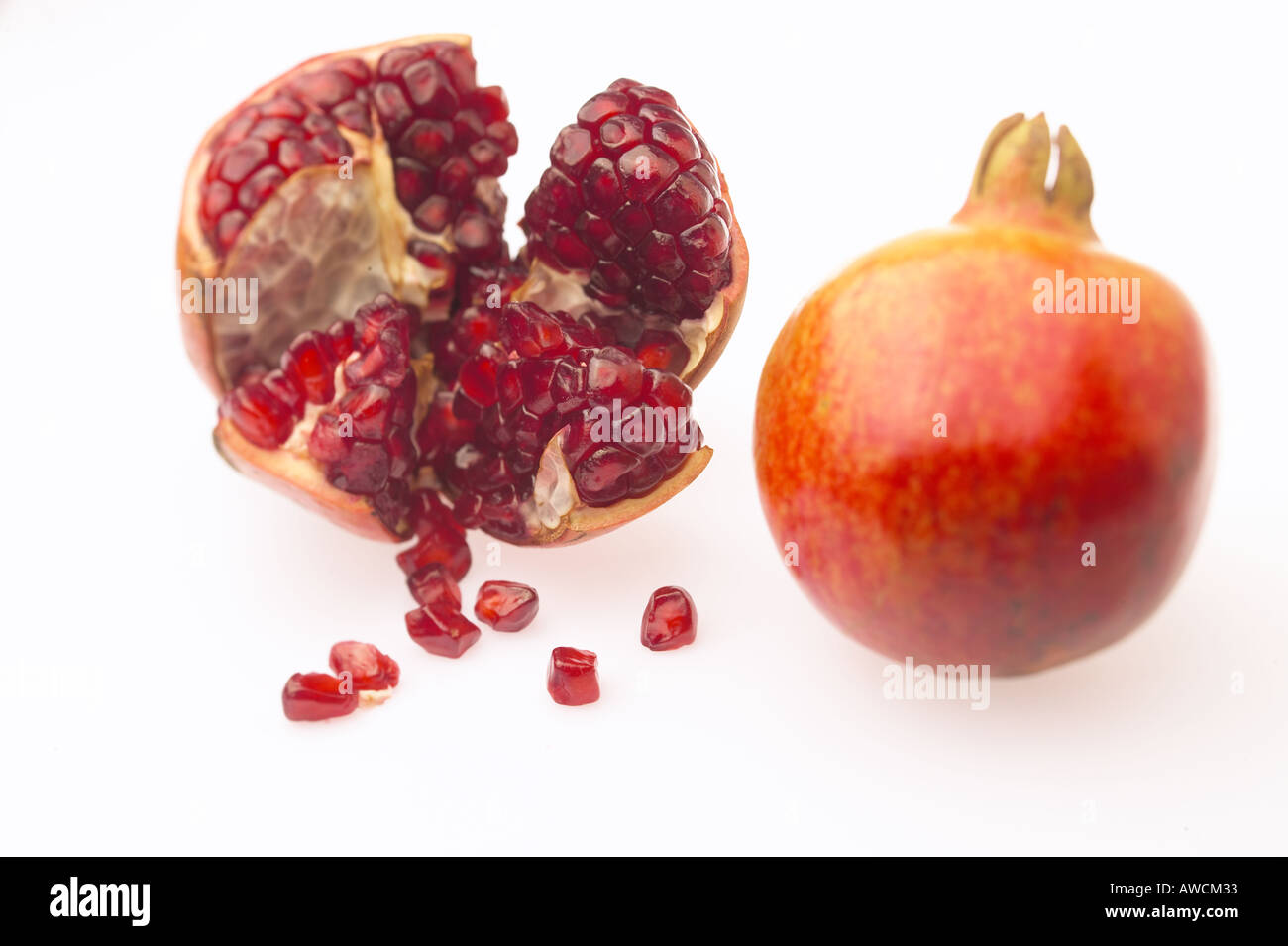 One closed and one opened fruit red color Pomegranate seeds scattered ...