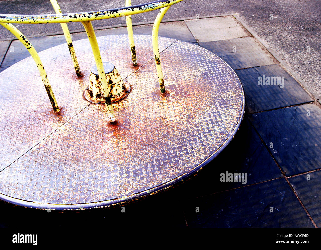 Round metal footplate of an old rusting yellow round-about in a ...