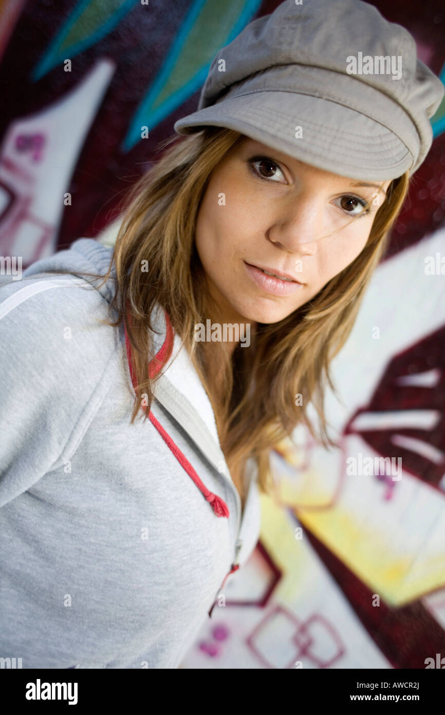 Portrait of woman with cap in front of a graffiti wall Stock Photo - Alamy