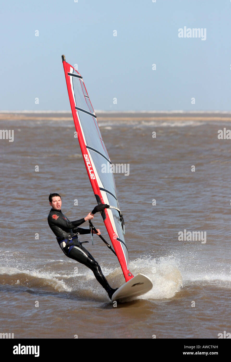 Windsurfer with a red sail racing over the waves Stock Photo - Alamy
