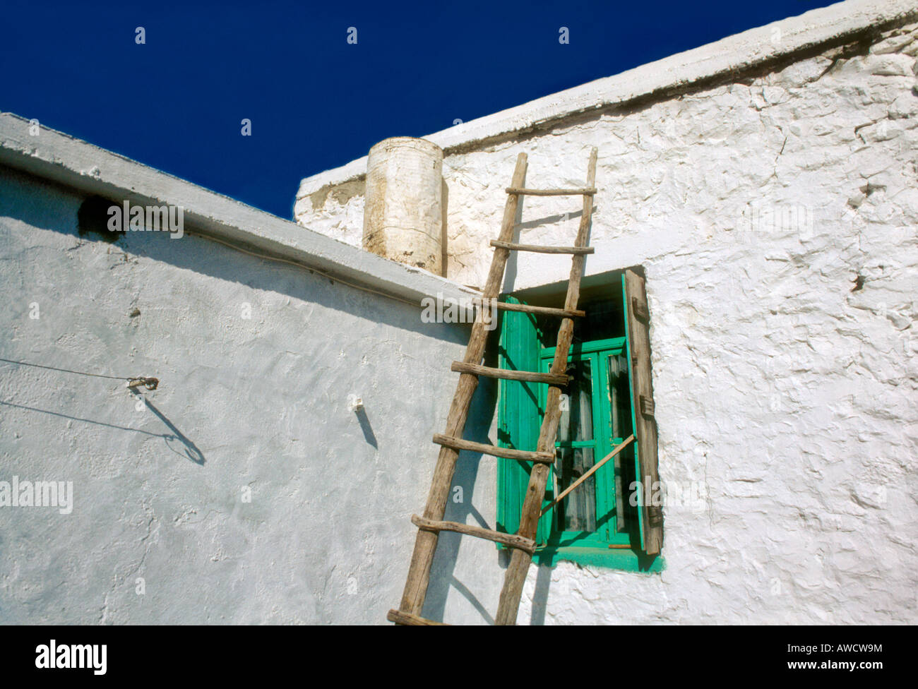 old wooden ladder up the side of white washed limestone walls of small ...
