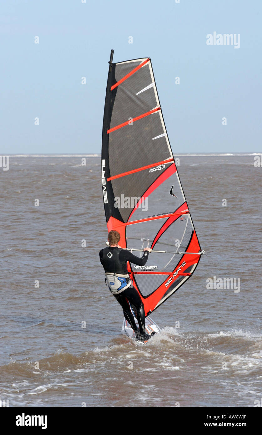 Windsurfer with a red sail racing over the waves Stock Photo - Alamy