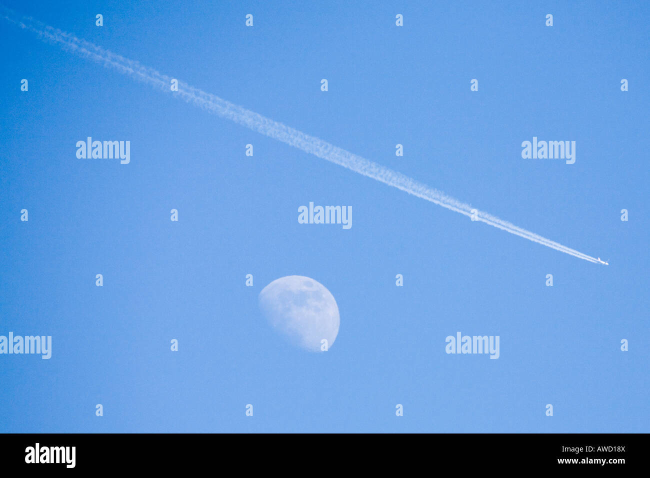 Aircraft flying over moon leaving vapour trail during the day Shot from ...