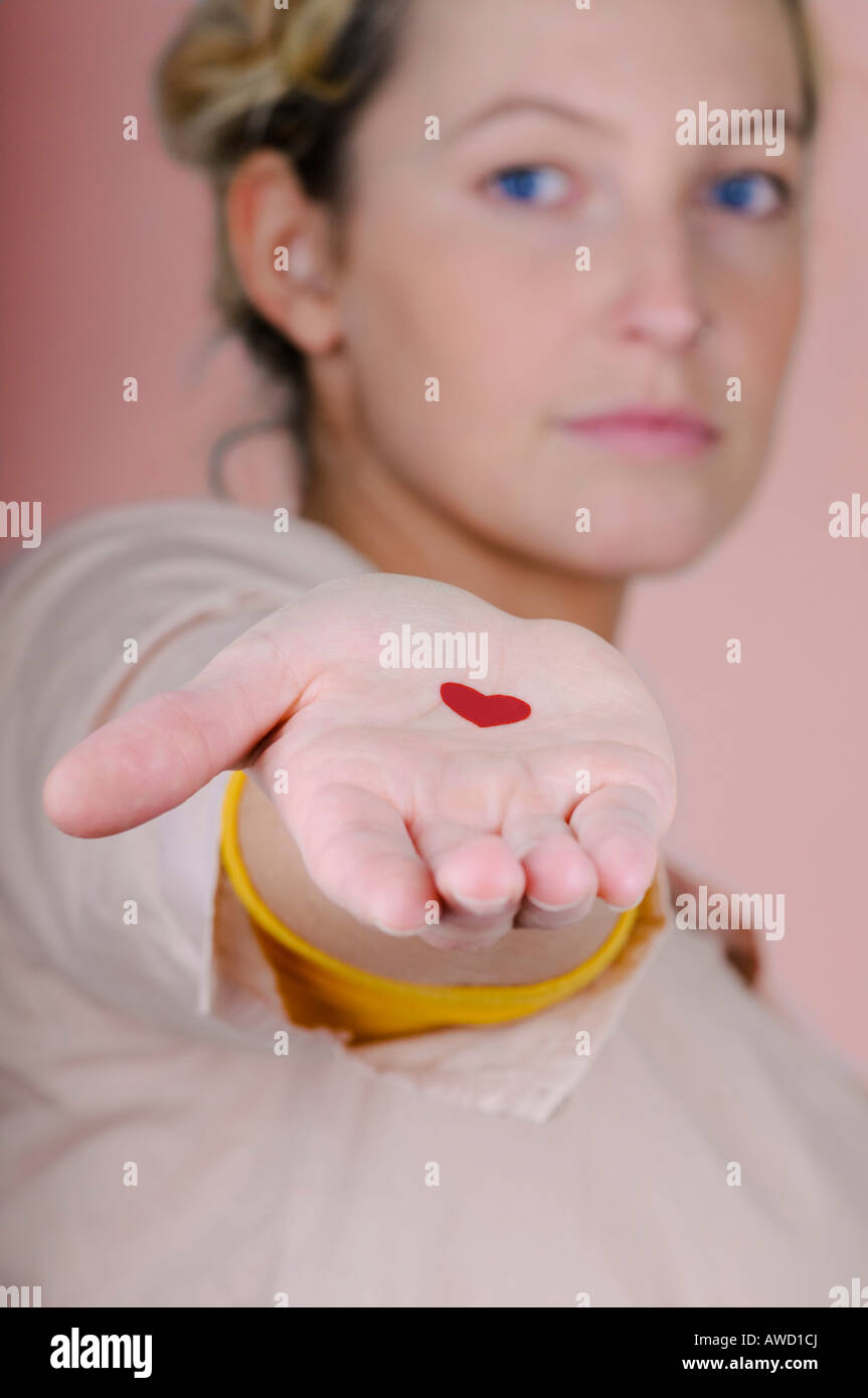 Young woman holding heart on palm, arm outstretched Stock Photo - Alamy