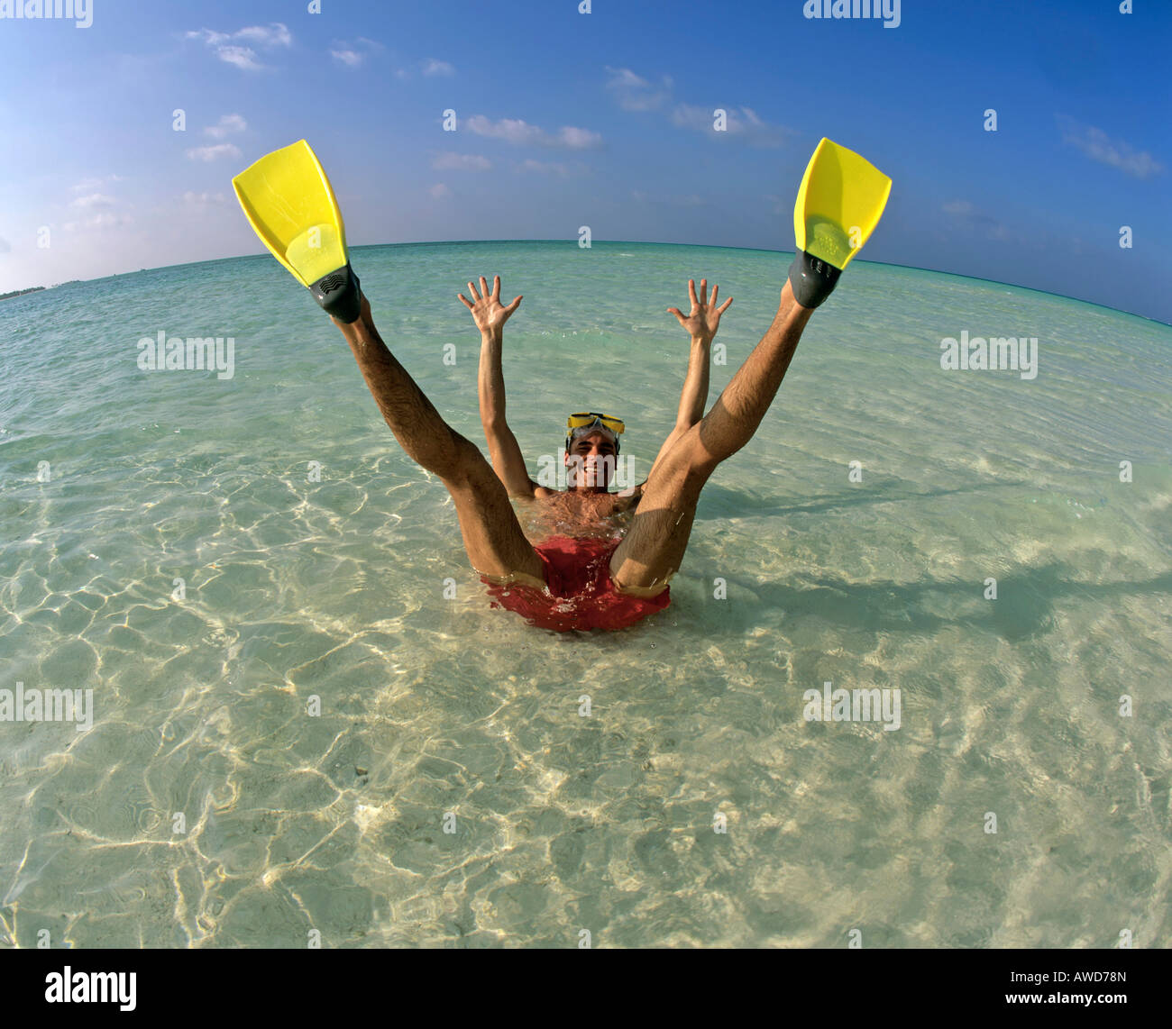Young man wearing flippers laying in shallow water, vacation, Maldives ...