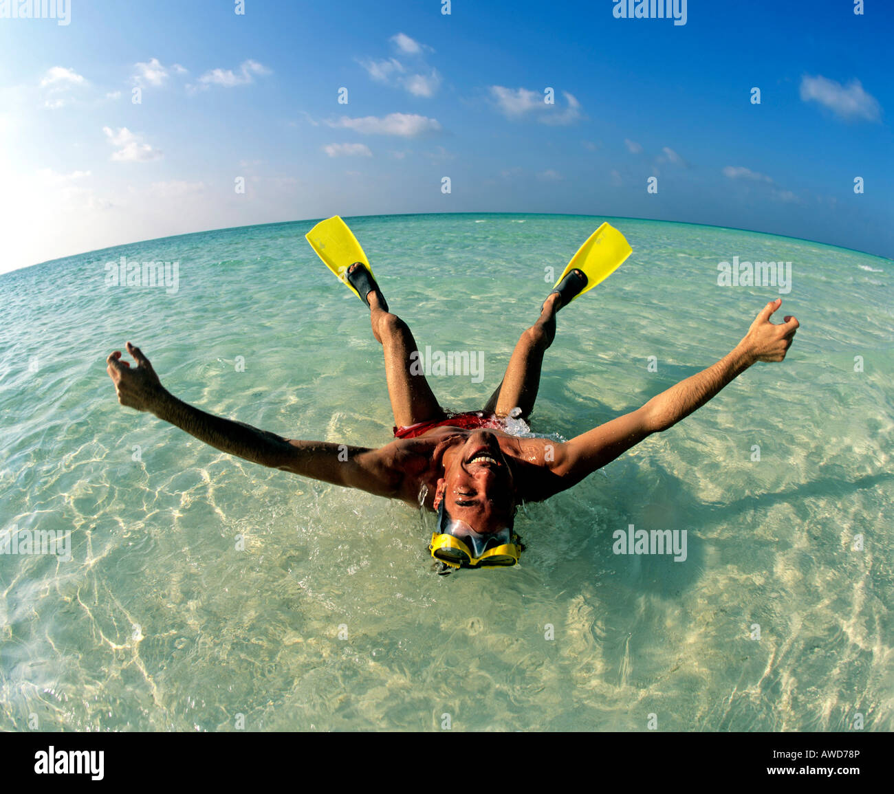 Young man wearing flippers laying in shallow water, vacation, Maldives ...