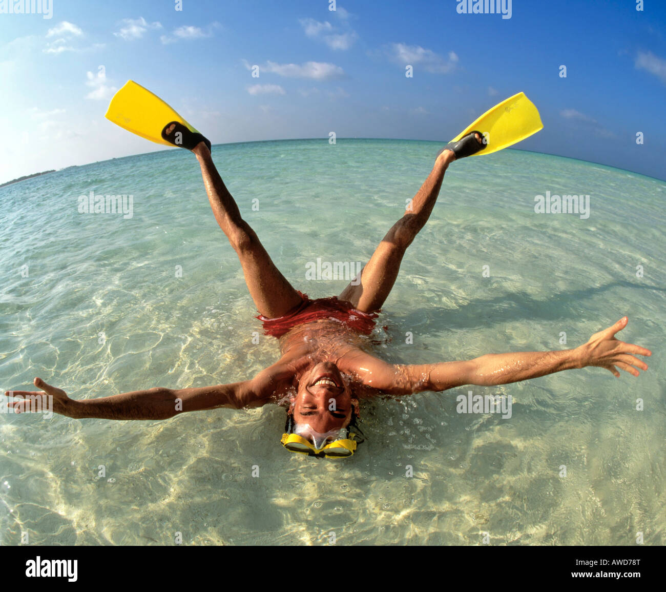 Young man wearing flippers laying in shallow water, vacation, Maldives ...