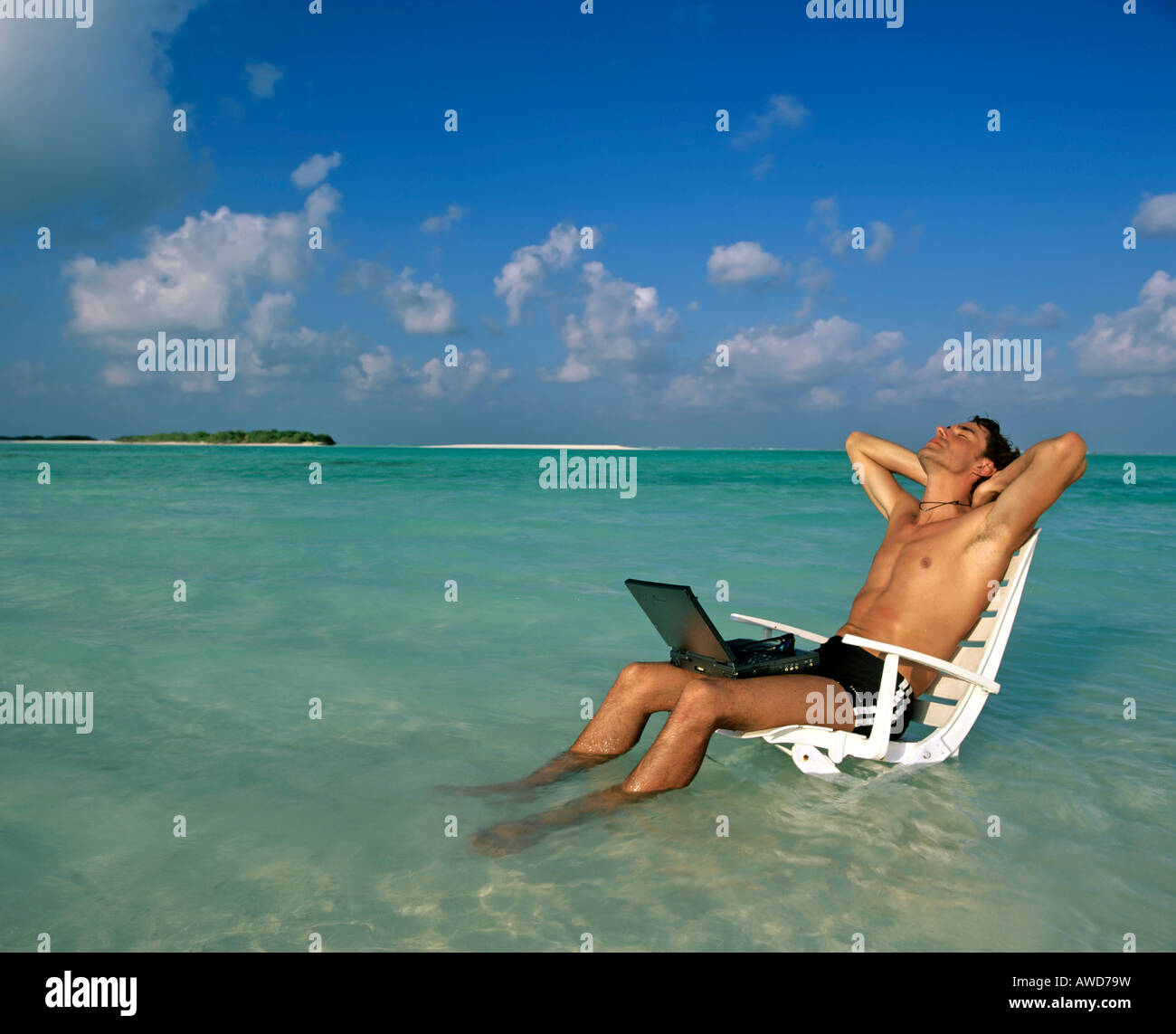 Young man with laptop sitting on deck chair, work and relaxation ...