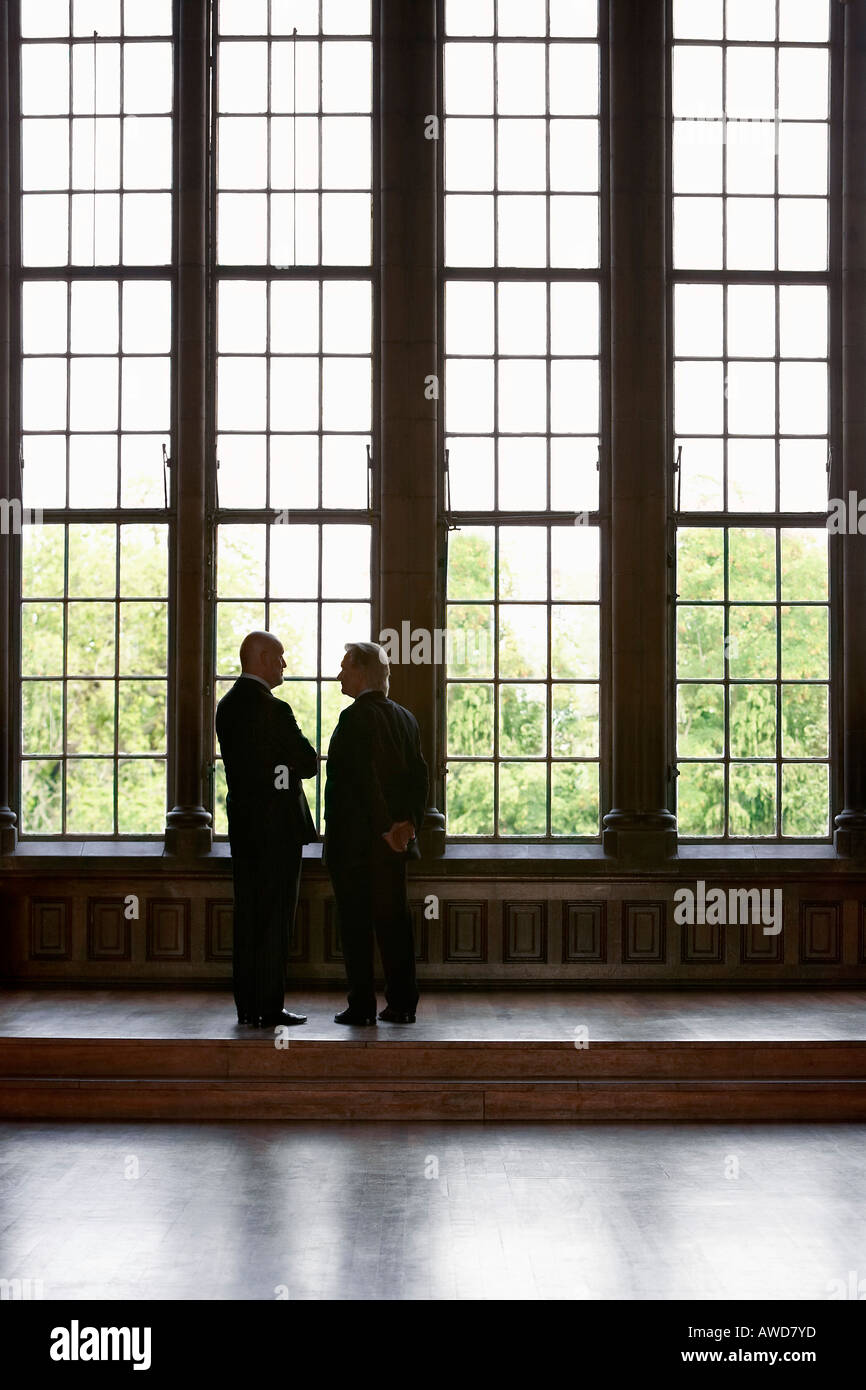 Two Men Conversing by tall windows Stock Photo - Alamy