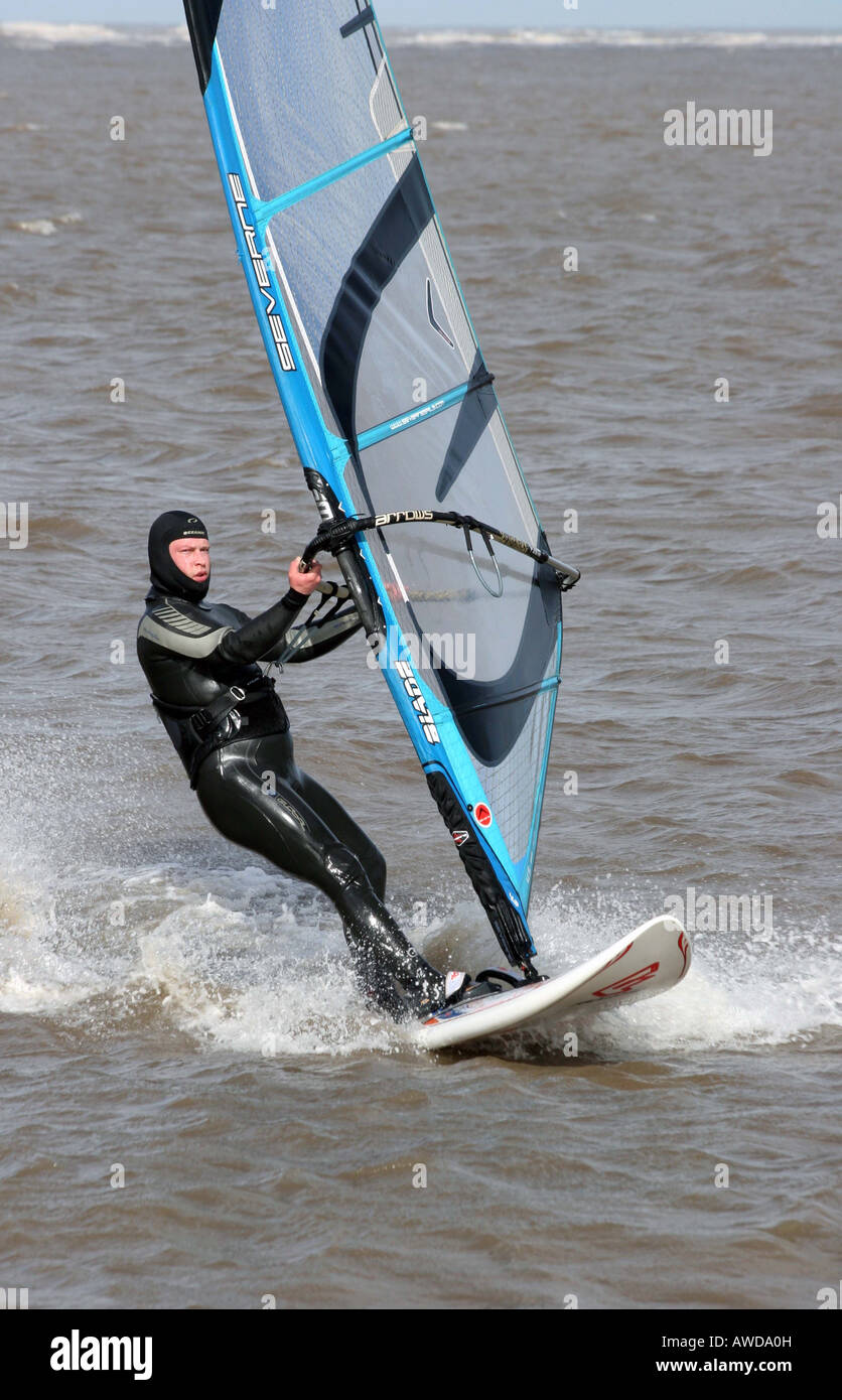 Windsurfer with a blue sail racing over the waves Stock Photo - Alamy