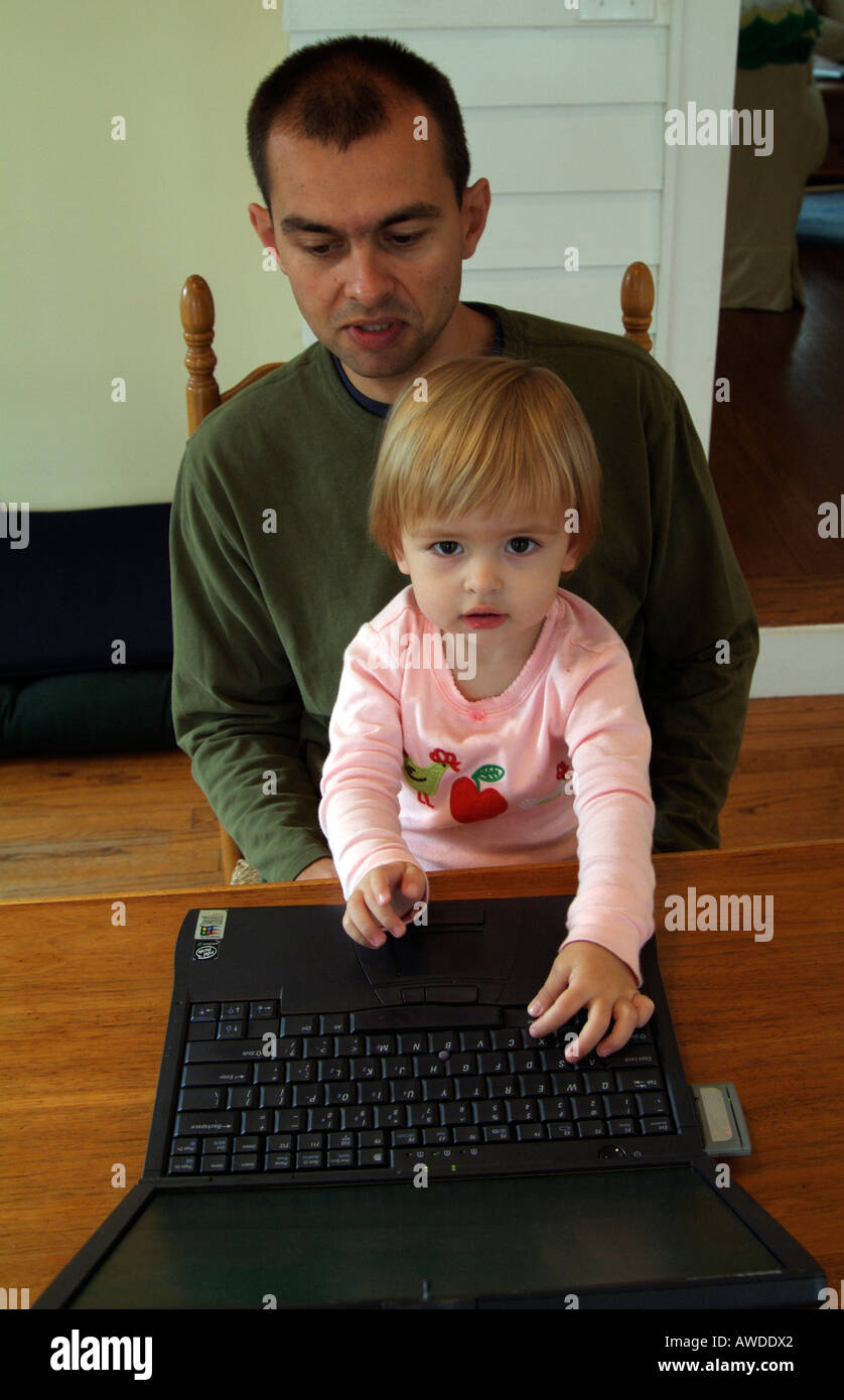 A little girl with fingers on the keypad learning to use a laptop ...