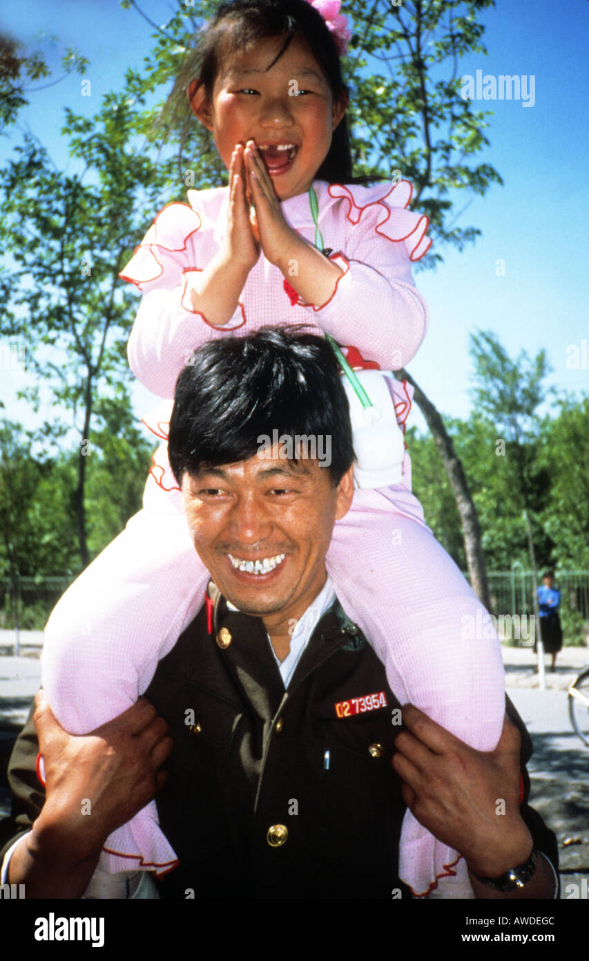 Chinese soldier carrying his daughter on his shoulders to view a parade ...