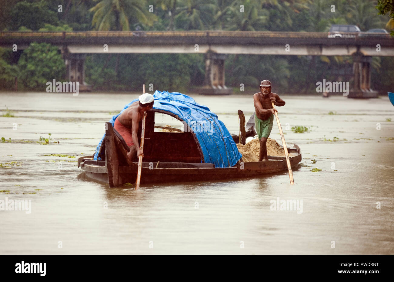 Rural men plying a traditional wooden canoe with cargo of sand in ...