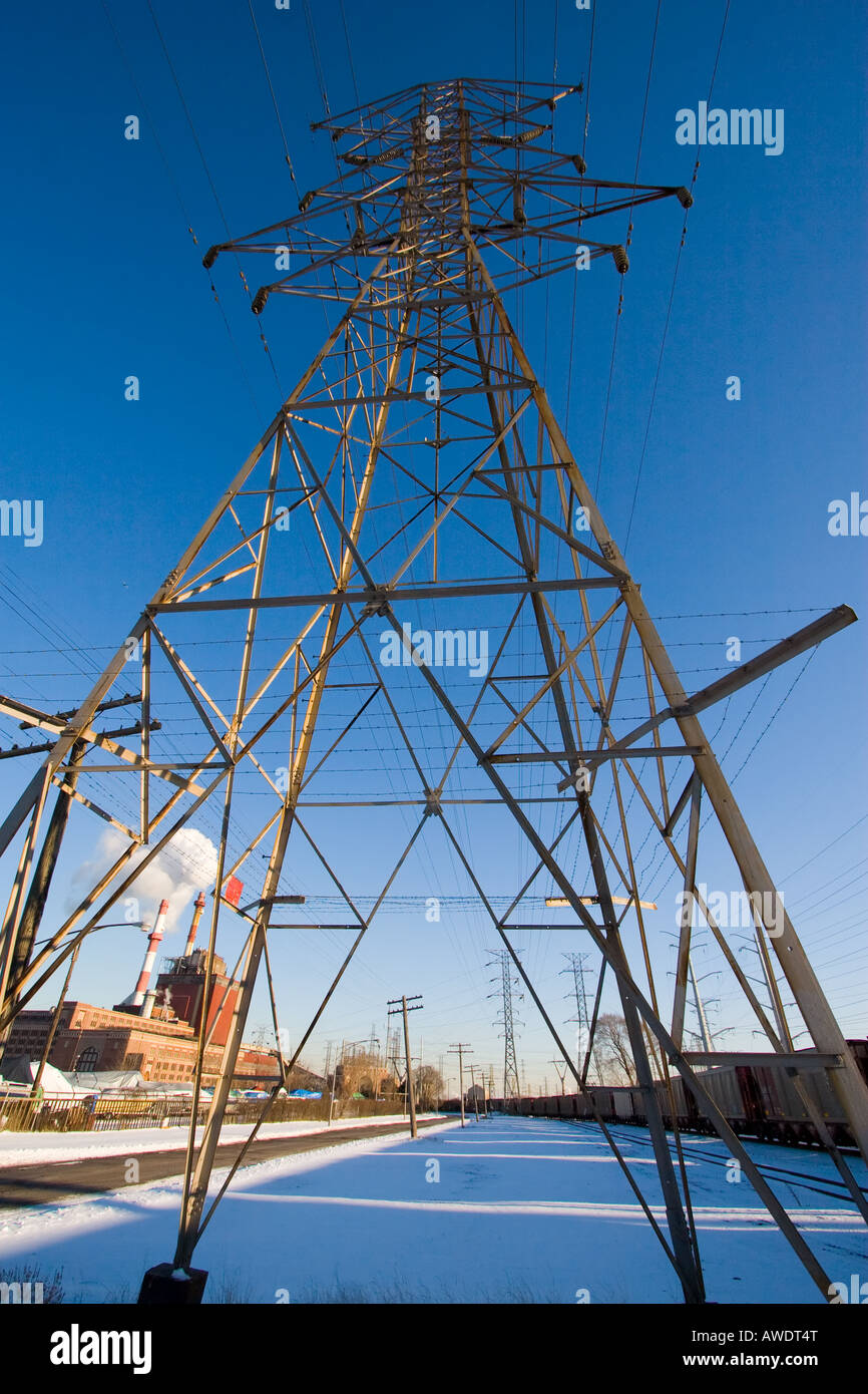 An electric transmission tower stands tall over a power plant Stock ...