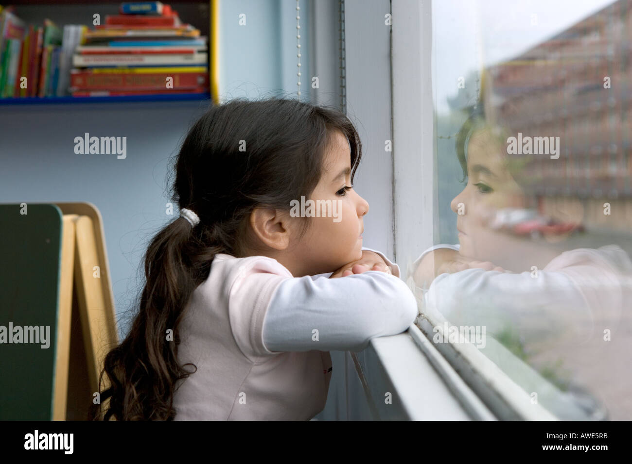Sad girl is looking through the window Stock Photo - Alamy