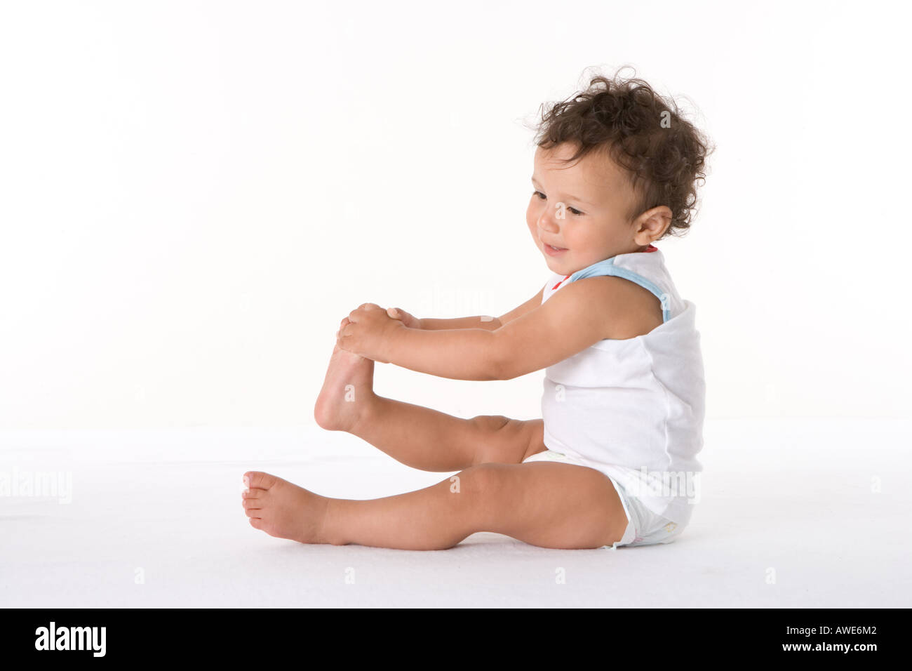 Little boy sitting on the floor holding one foot Stock Photo - Alamy