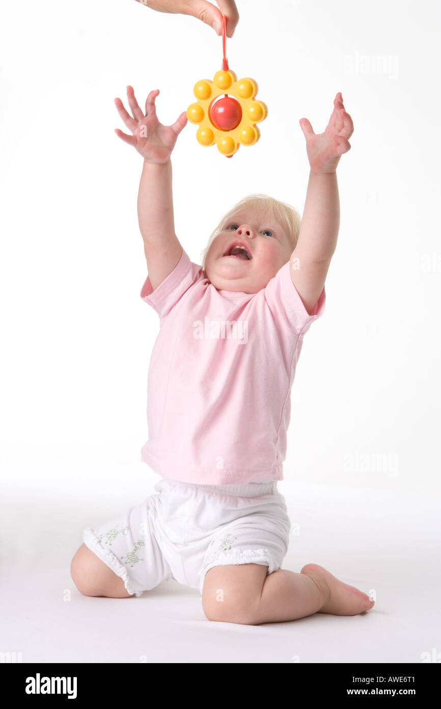Little girl reaching for a toy Stock Photo - Alamy