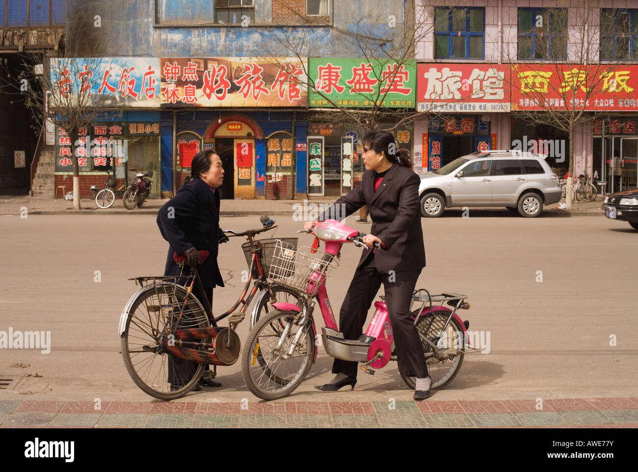 Two women with bikes, chat on the street in Pingyao, People's Republic ...