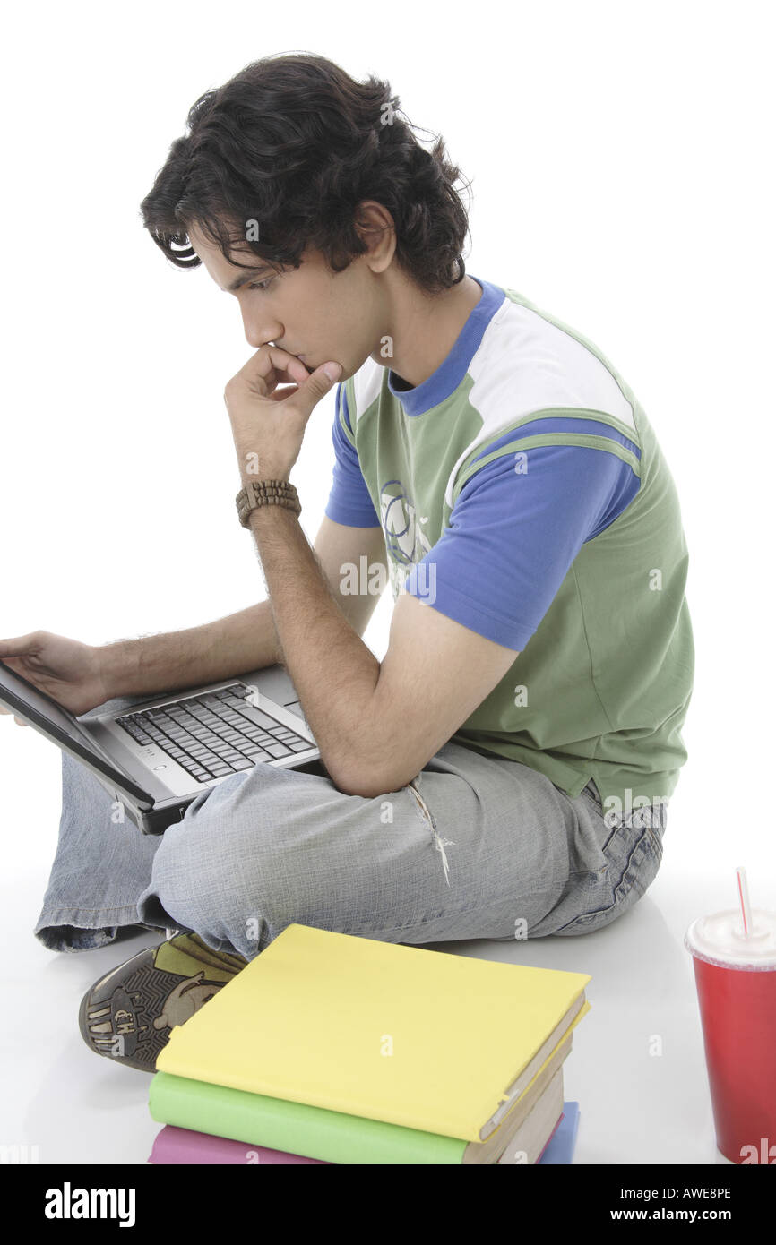 Teenage boy sitting and thinking and working on laptop computer Stock ...