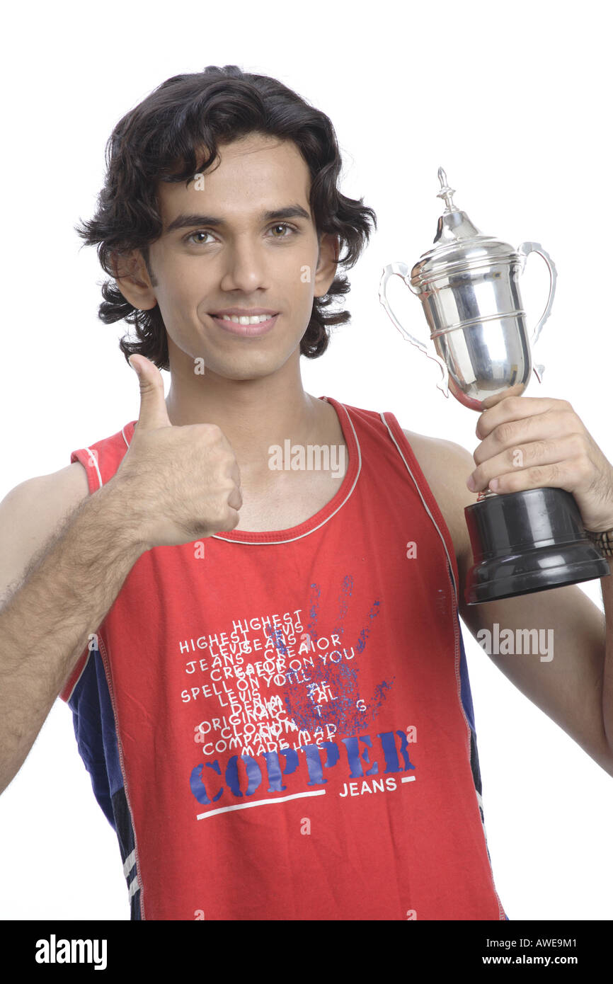 ANG200547 Teenage boy winning trophy cup success showing thumb as ...