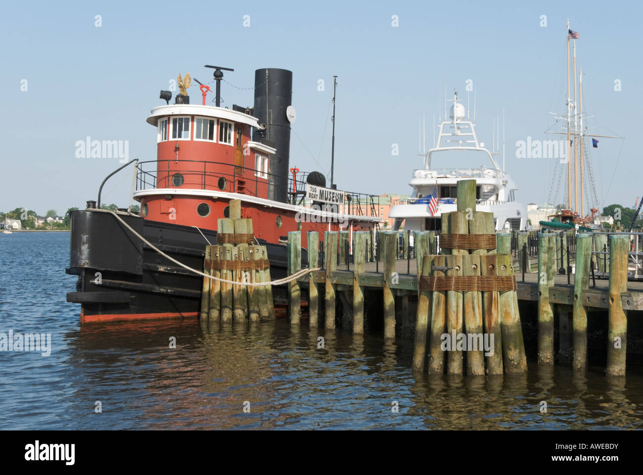 Tugboat tied to wooden harbor dock at morning, port of Norfolk ...