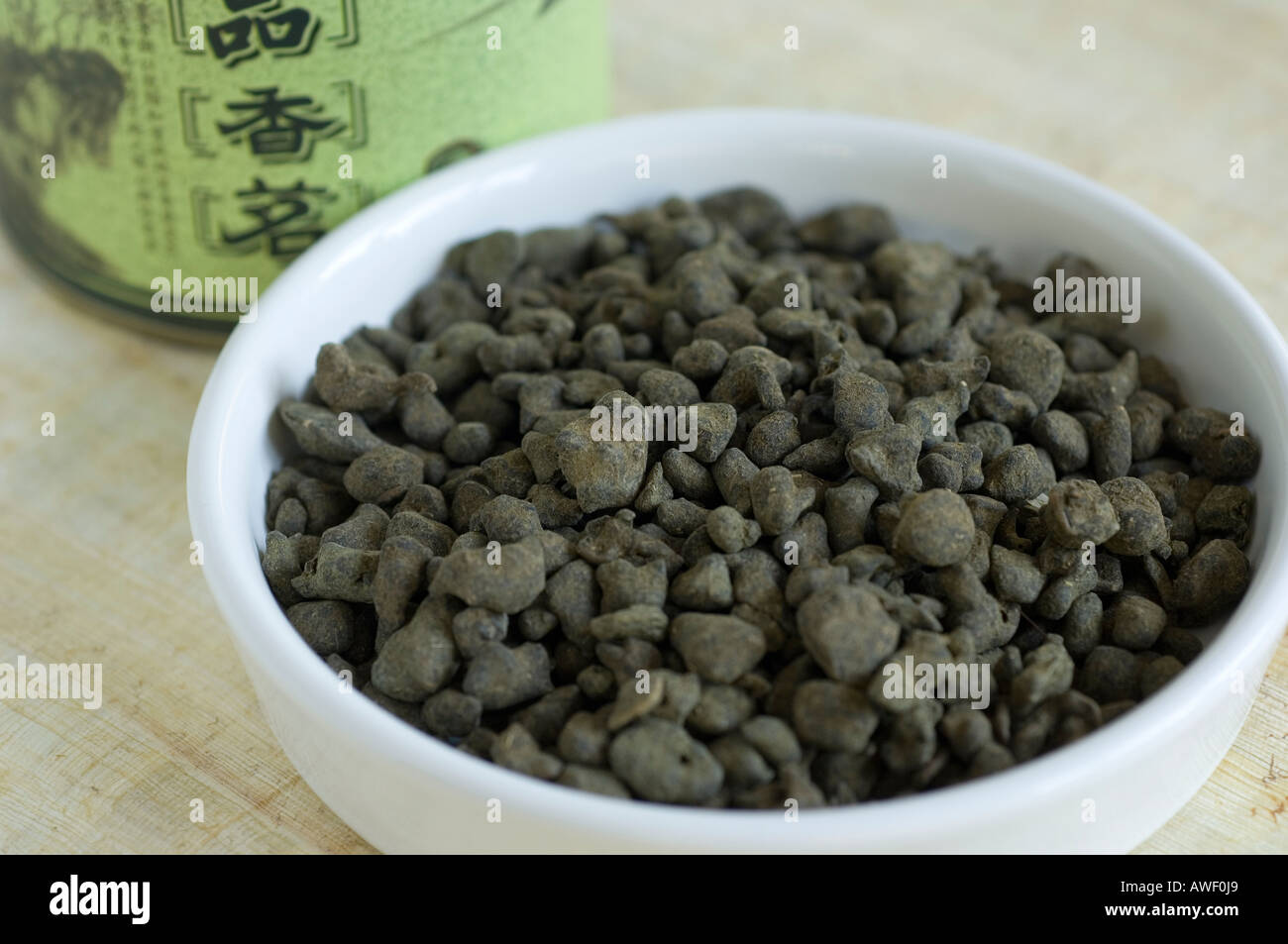 gunpowder green tea in a white bowl with packaging in the background ...