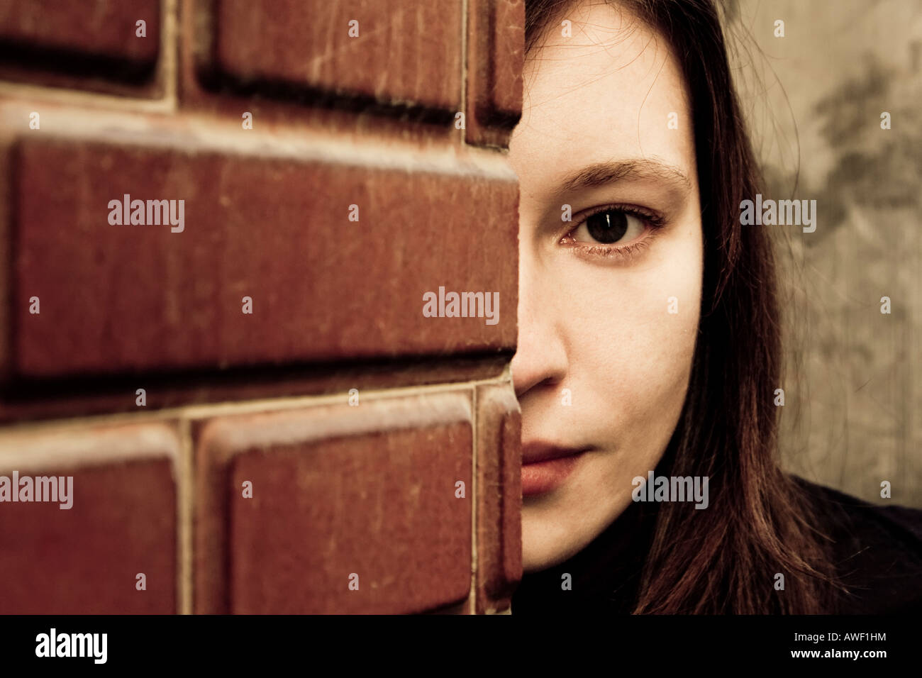 Woman looking behind a brick wall Stock Photo - Alamy