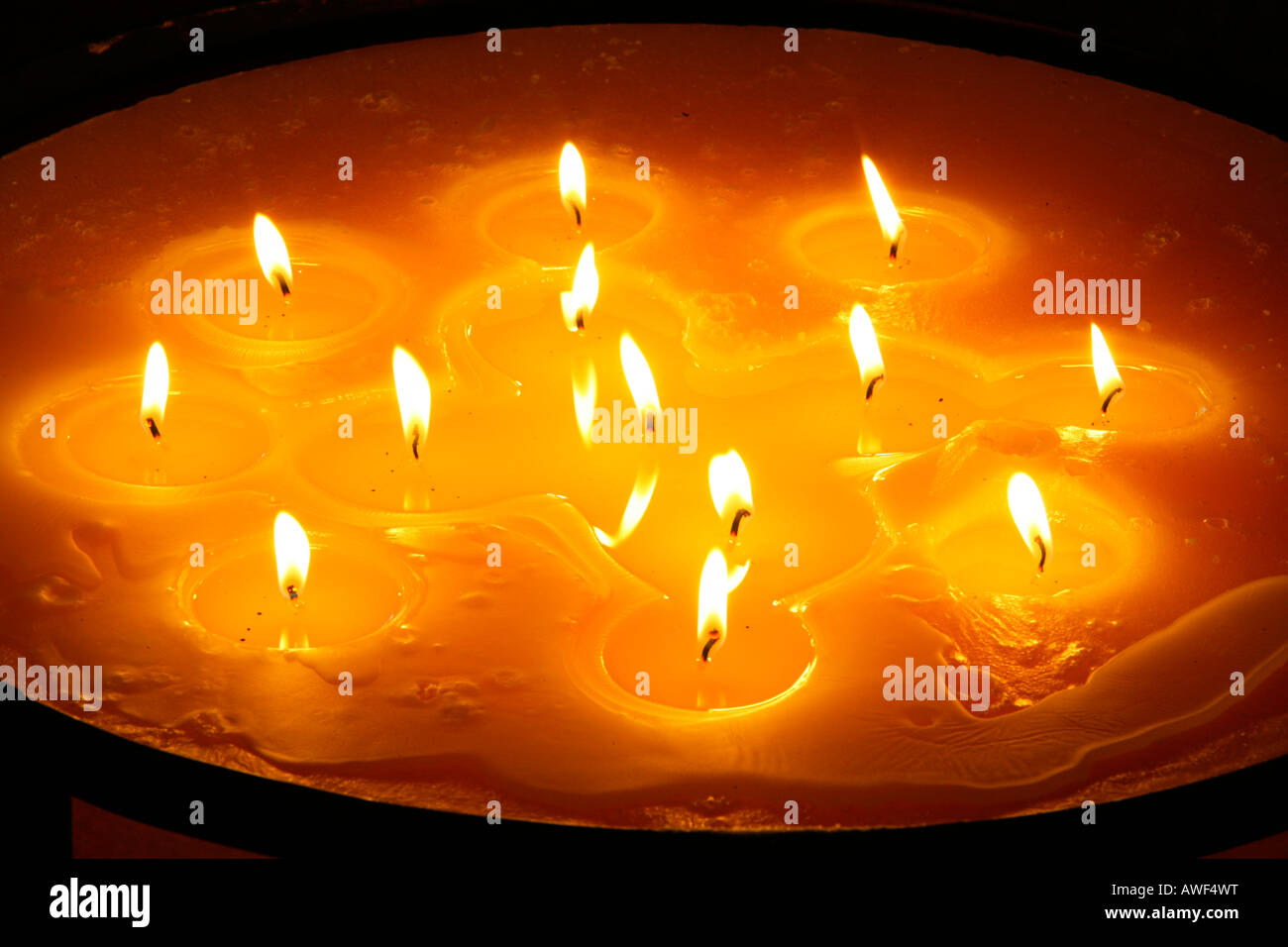 Large candle with multiple burning wicks Stock Photo - Alamy