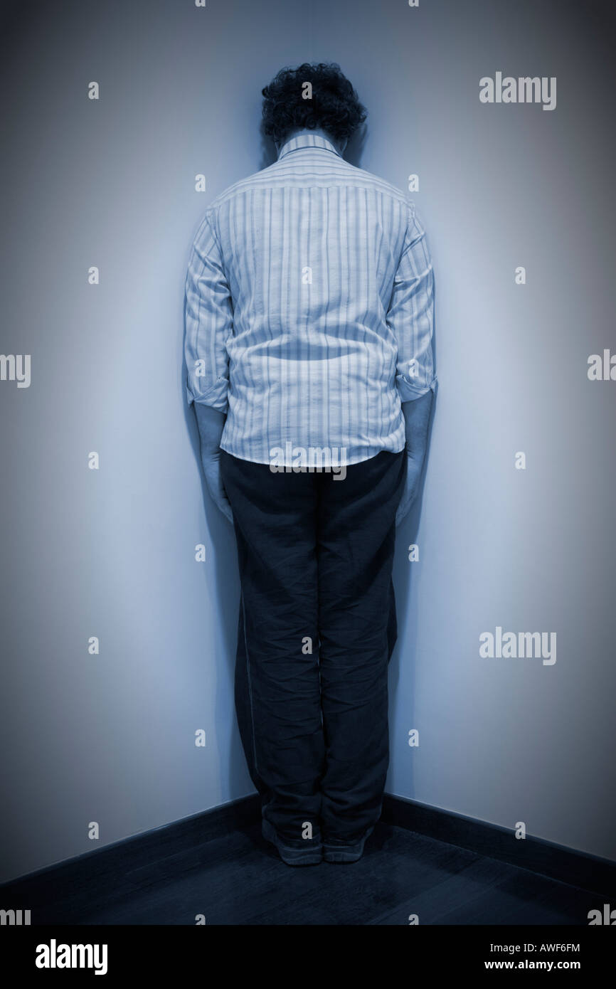 Man standing in room corner facing the wall. Blue toned image Stock ...
