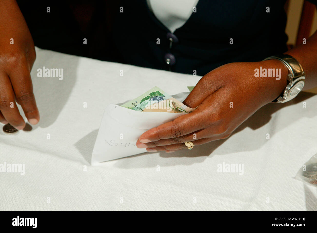 Hands stuffing money into an envelope for donation, Francistown ...