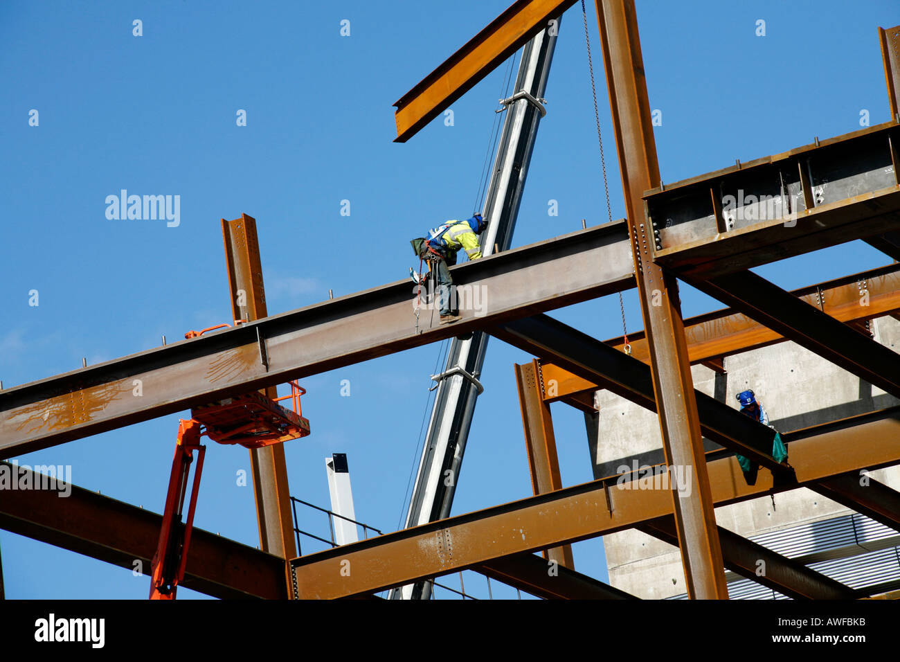 a construction worker guiding in large steel girders on a building site ...
