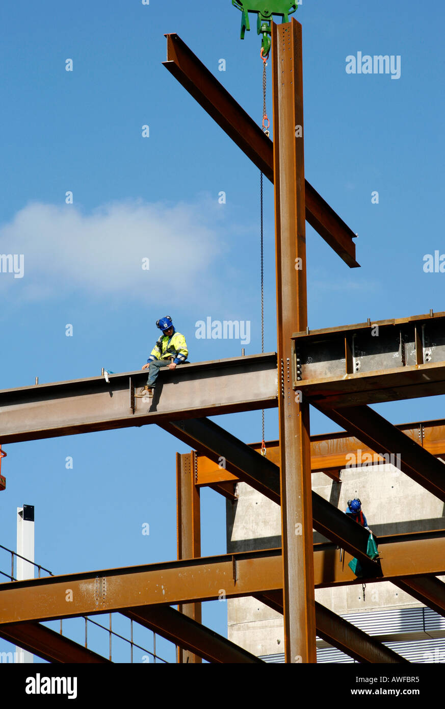 A constuction worker sits high up on steel girders on a large building ...