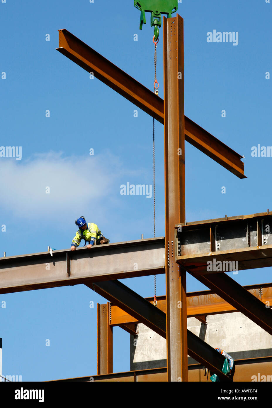 a construction worker placing steel girders high up on a large scale ...