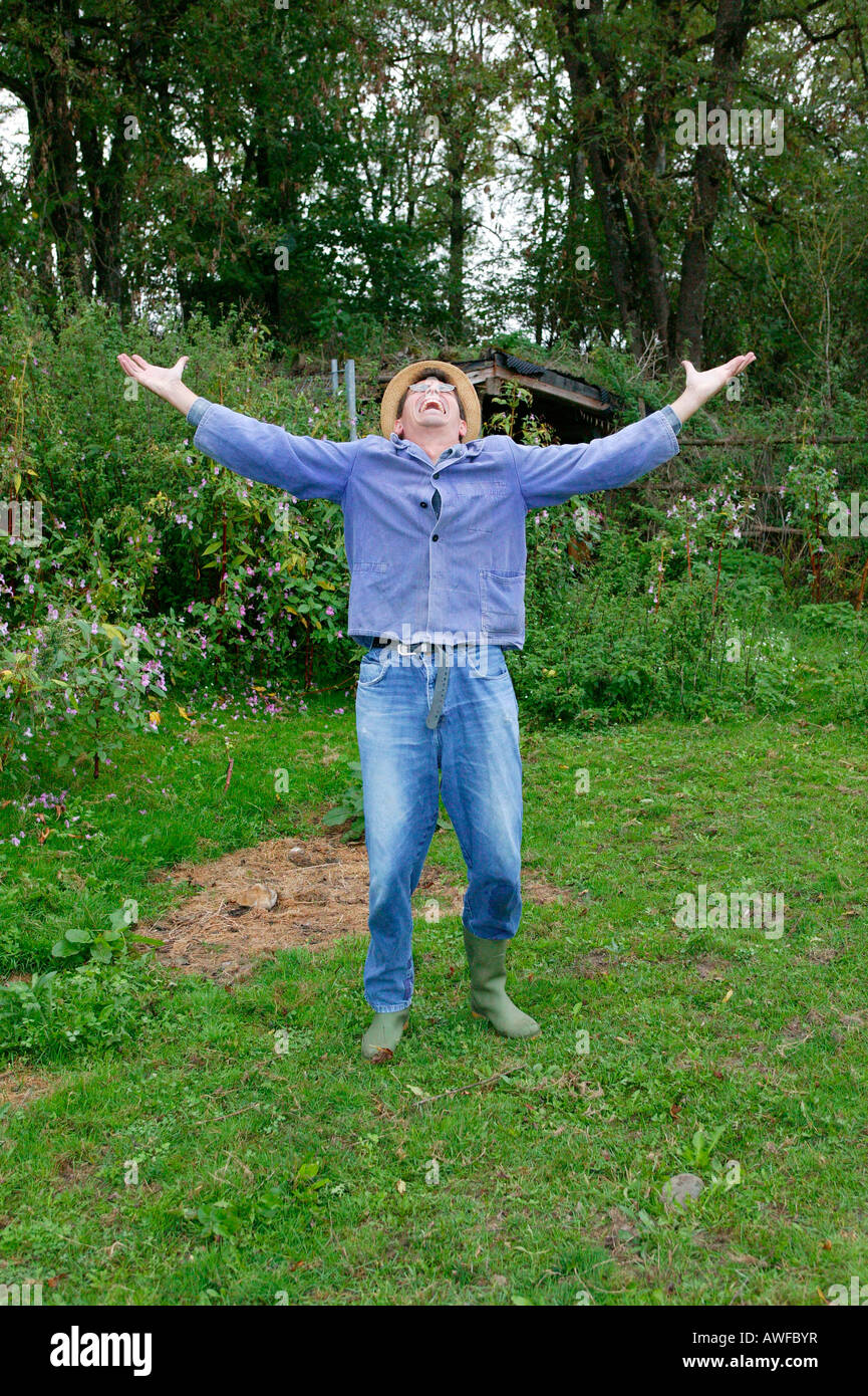 German farmer with arms stretched out looking up the sky, Upper Bavaria ...