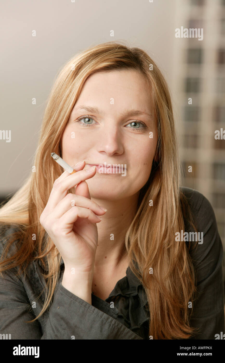 Young blonde woman smoking a cigarette, smiling Stock Photo - Alamy