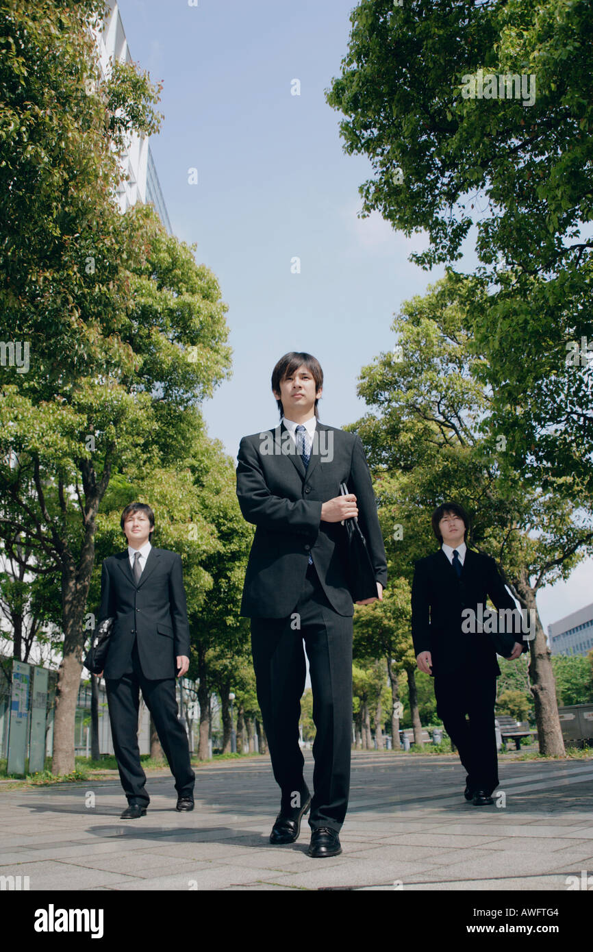 Three young men in suit walking on street Stock Photo - Alamy