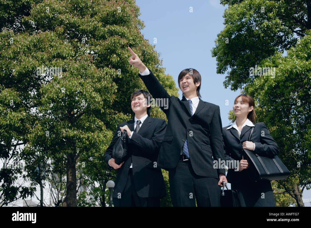A young man in suit pointing ahead with his friends standing aside ...