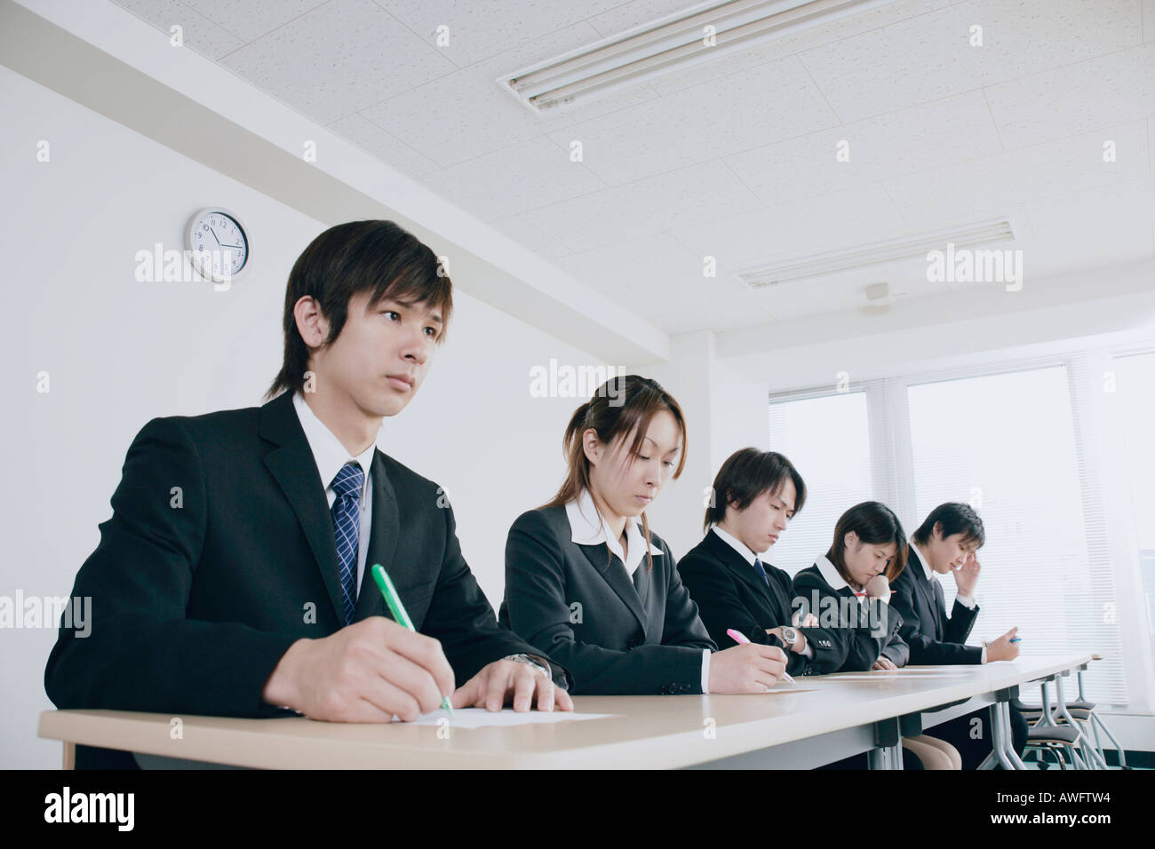 Five young people writing on exam paper Stock Photo - Alamy